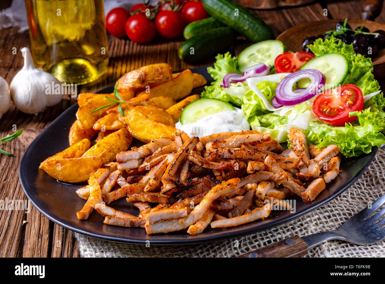 Rustic gyros plate it green salad and potato wedges Stock Photo - Alamy