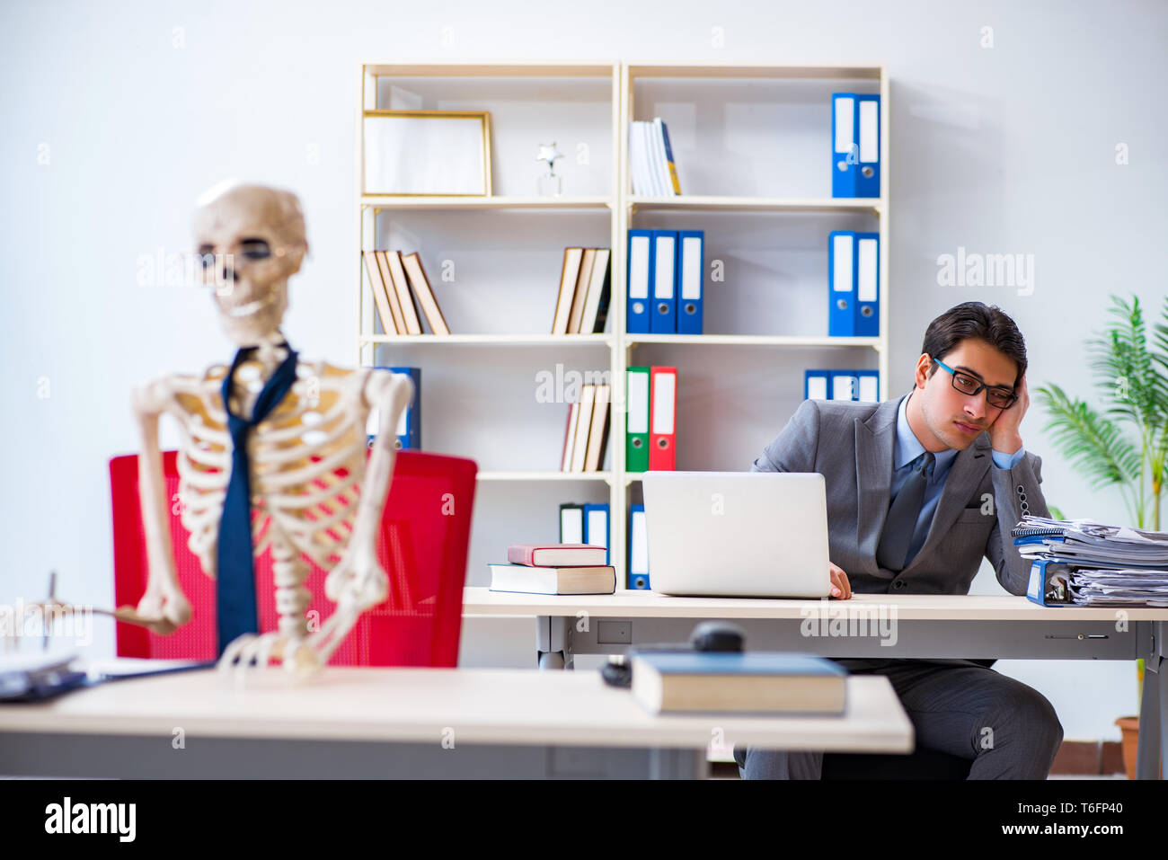 Businessman working with skeleton in office Stock Photo - Alamy