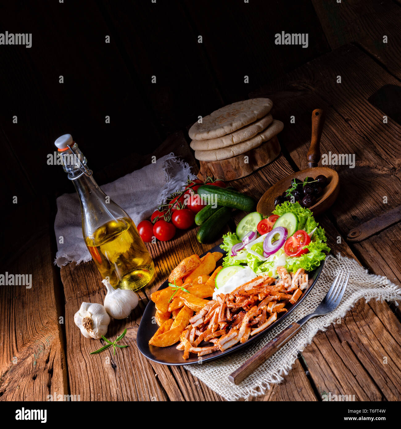 Rustic gyros plate it green salad and potato wedges Stock Photo - Alamy