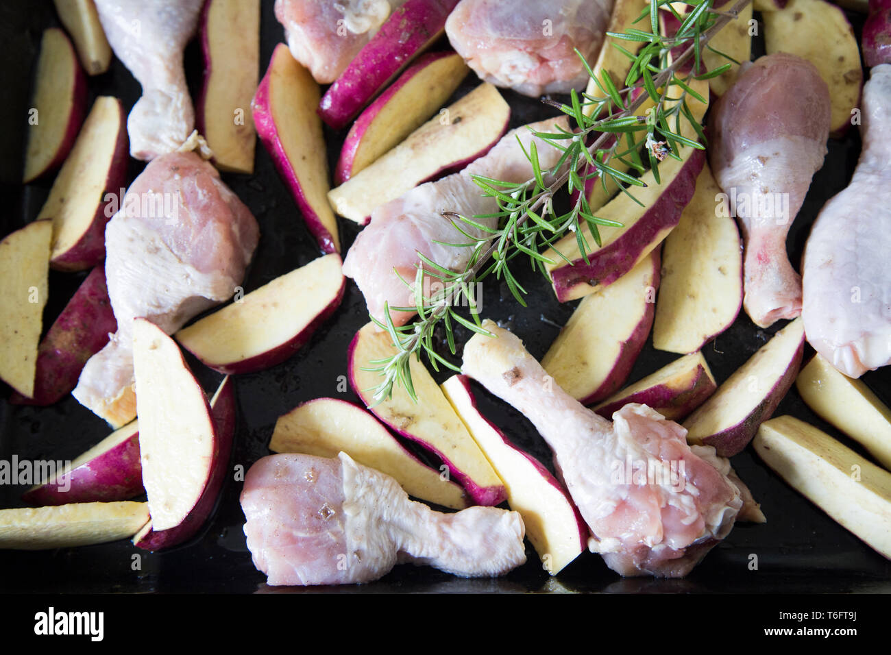 Raw organic chicken drumsticks and red kumara on an oven tray ready to ...