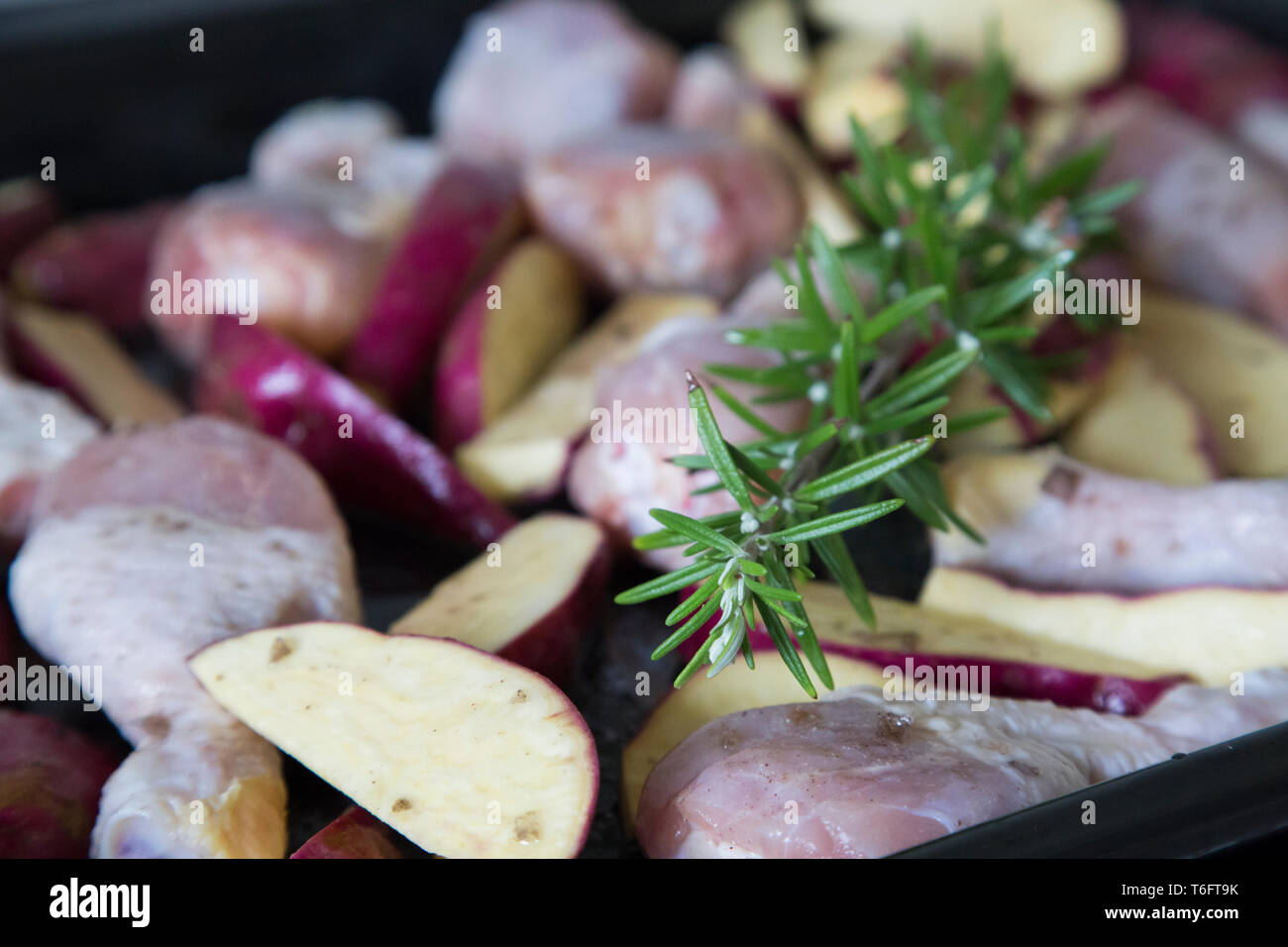 Raw organic chicken drumsticks and red kumara on an oven tray ready to ...