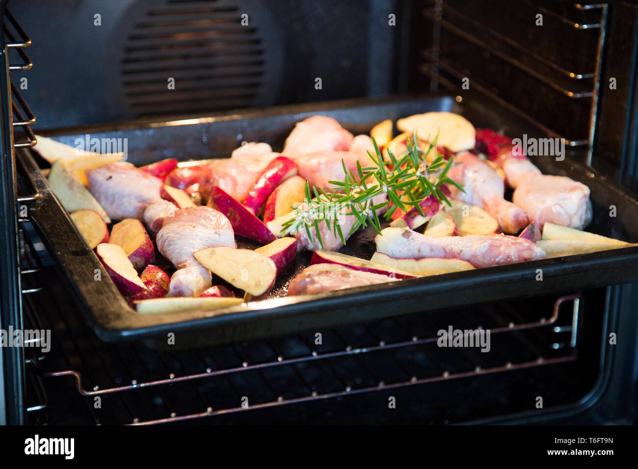 Raw organic chicken drumsticks and red kumara on an oven tray ready to ...