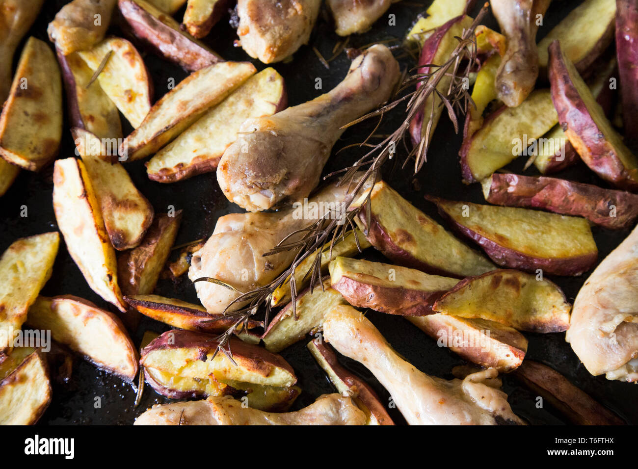 Roasting dish in oven with roasted cooked chicken drumsticks and red ...