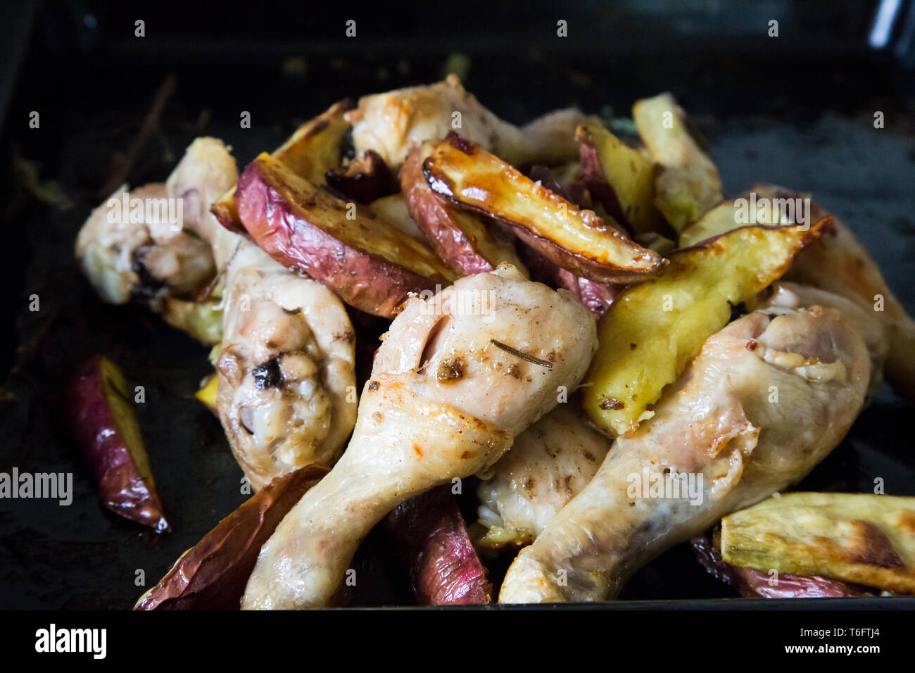 Roasting dish in oven with roasted cooked chicken drumsticks and red ...