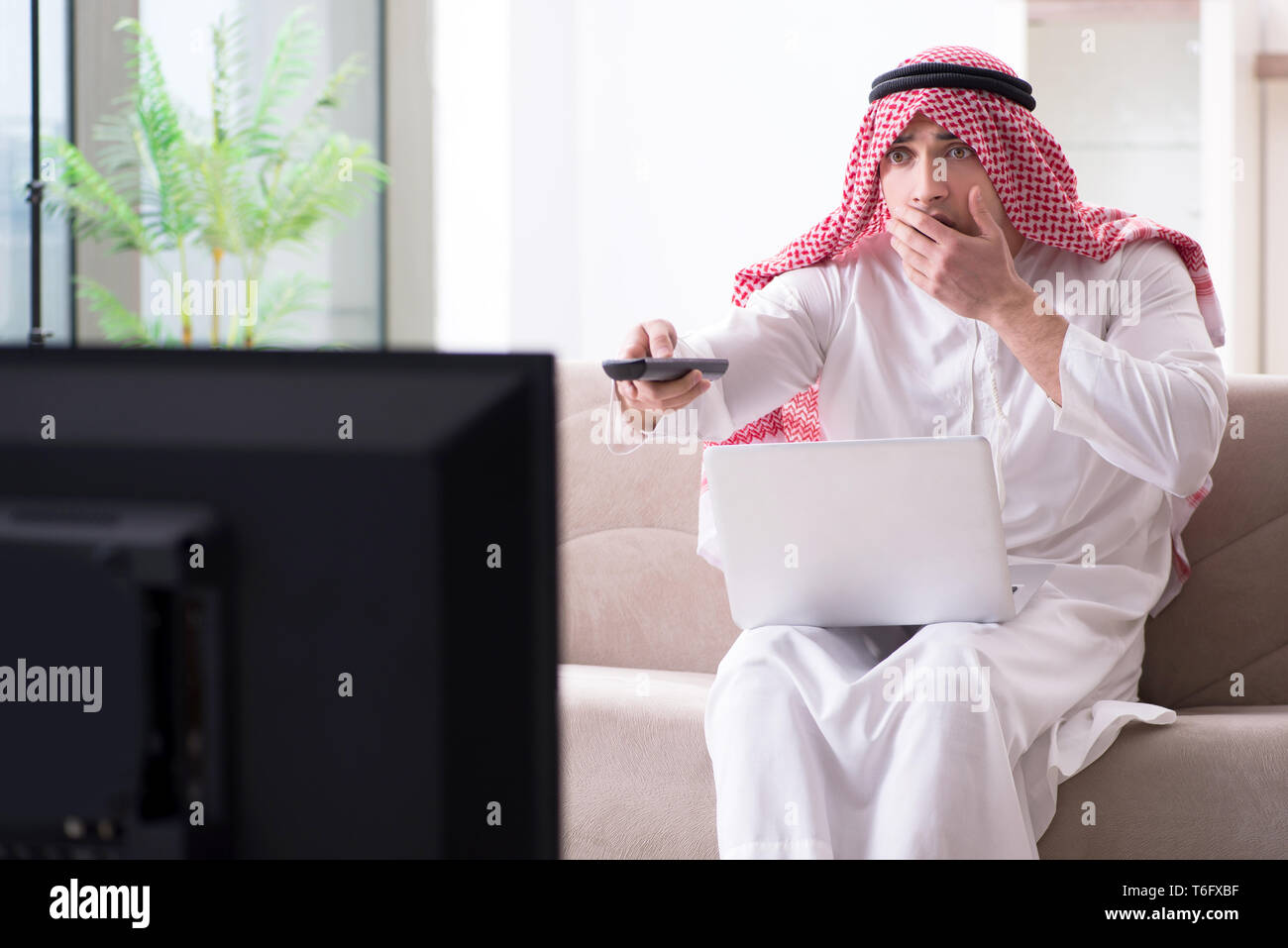 Arab man watching tv at home Stock Photo - Alamy