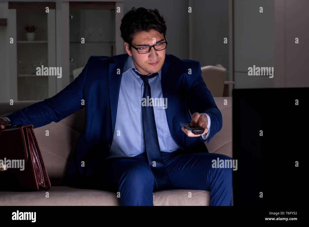 Businessman watching tv at night late Stock Photo - Alamy