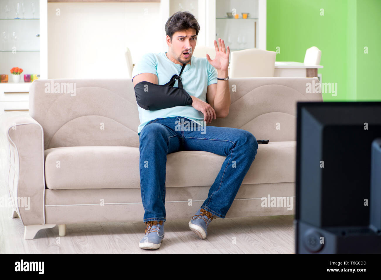 Arm injured man sitting on the sofa watching tv Stock Photo - Alamy