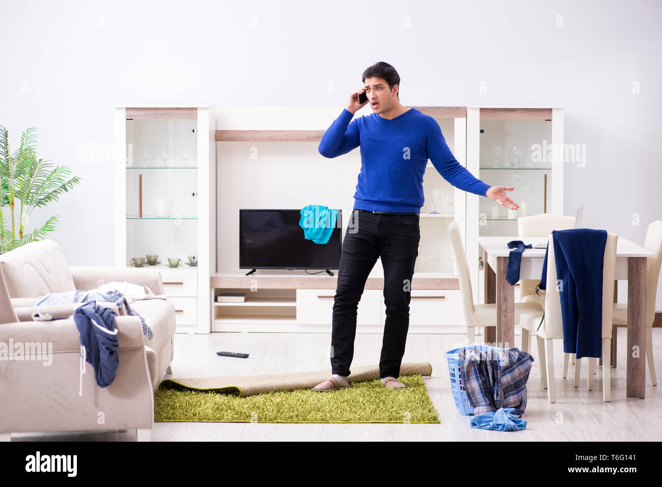 Young man collecting dirty clothing for laundry Stock Photo - Alamy