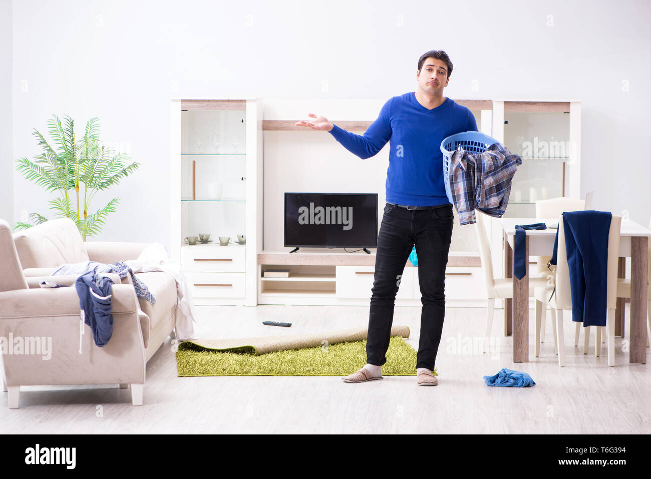 Young man collecting dirty clothing for laundry Stock Photo - Alamy