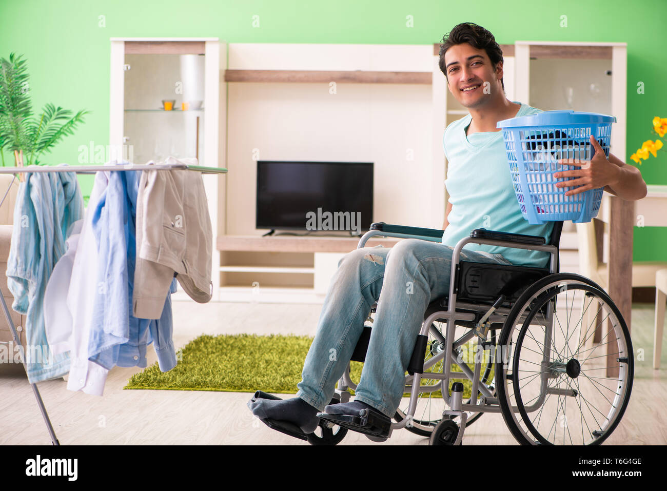 Disabled man on wheelchair doing laundry Stock Photo - Alamy