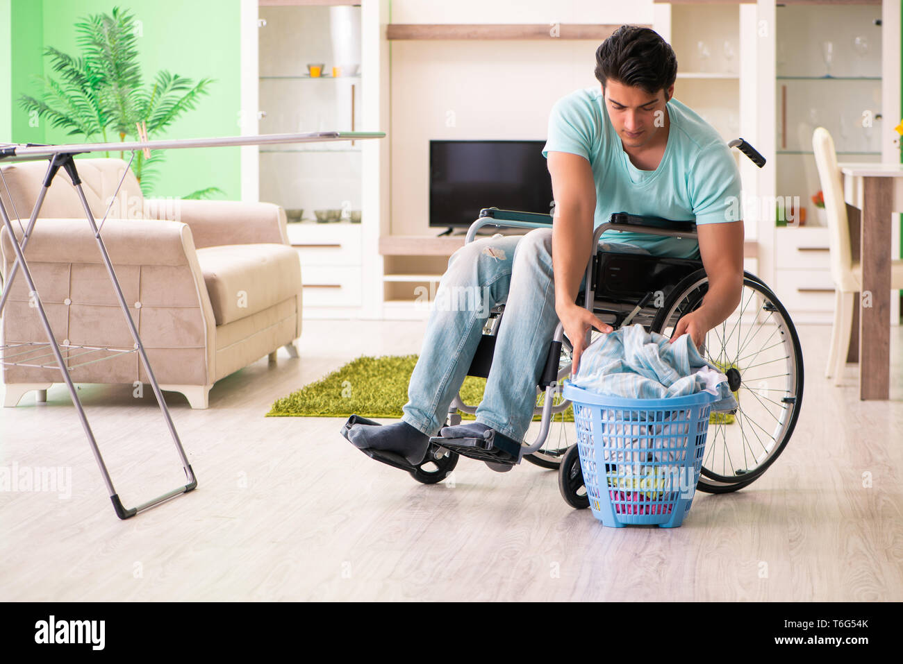 Disabled man on wheelchair doing laundry Stock Photo - Alamy