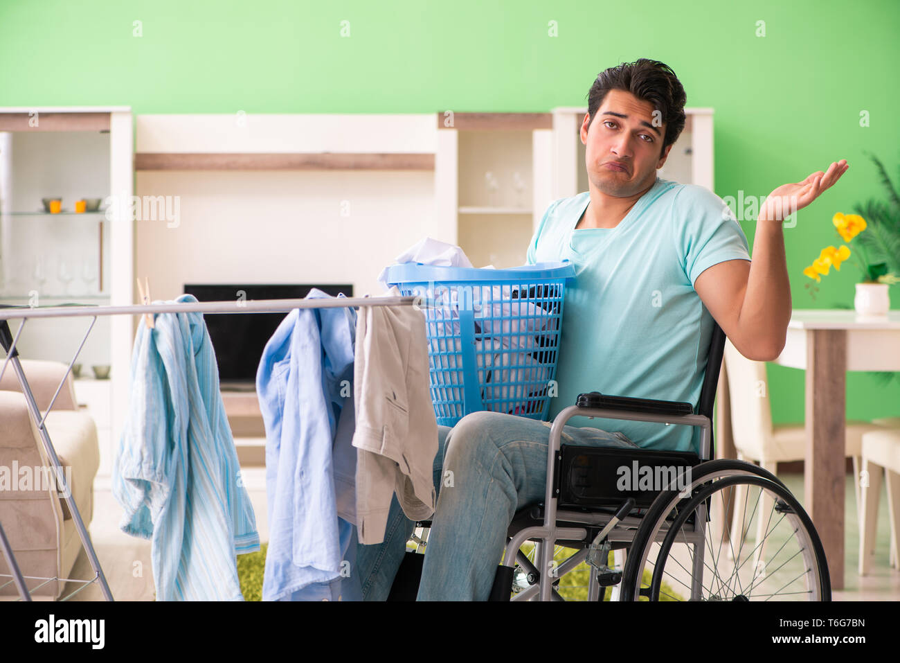 Disabled man on wheelchair doing laundry Stock Photo - Alamy