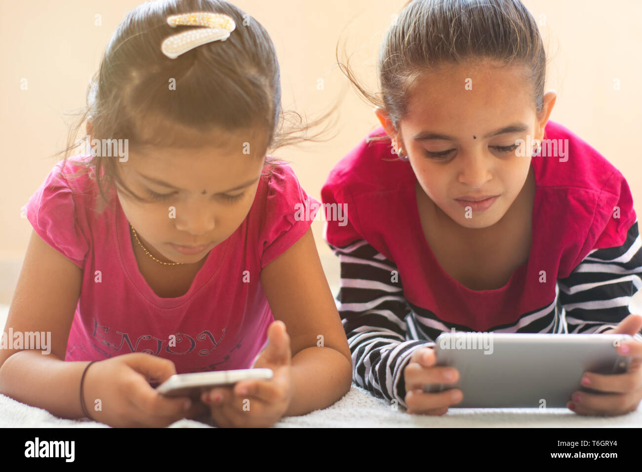 Two cute Indian children busy in watching Mobile phone on bed Stock ...