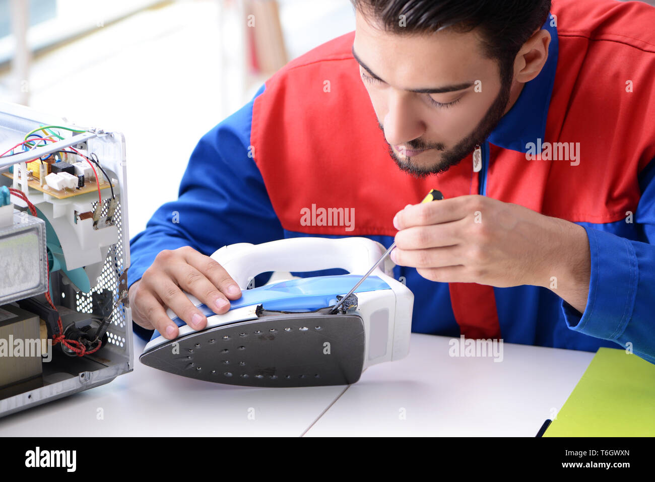 Man repairman repairing iron at service center Stock Photo - Alamy