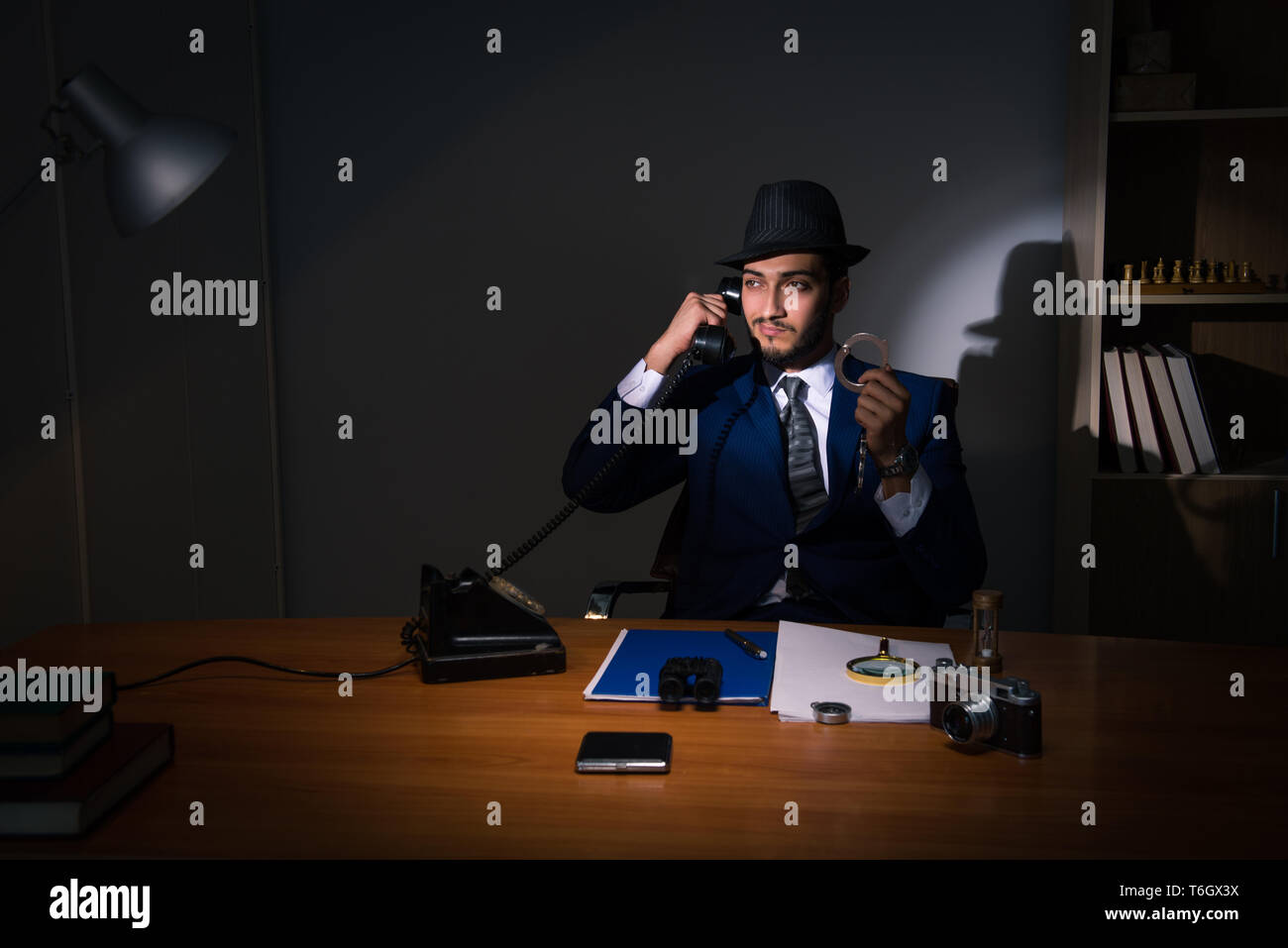 Detective sitting in dark room in vintage concept Stock Photo - Alamy