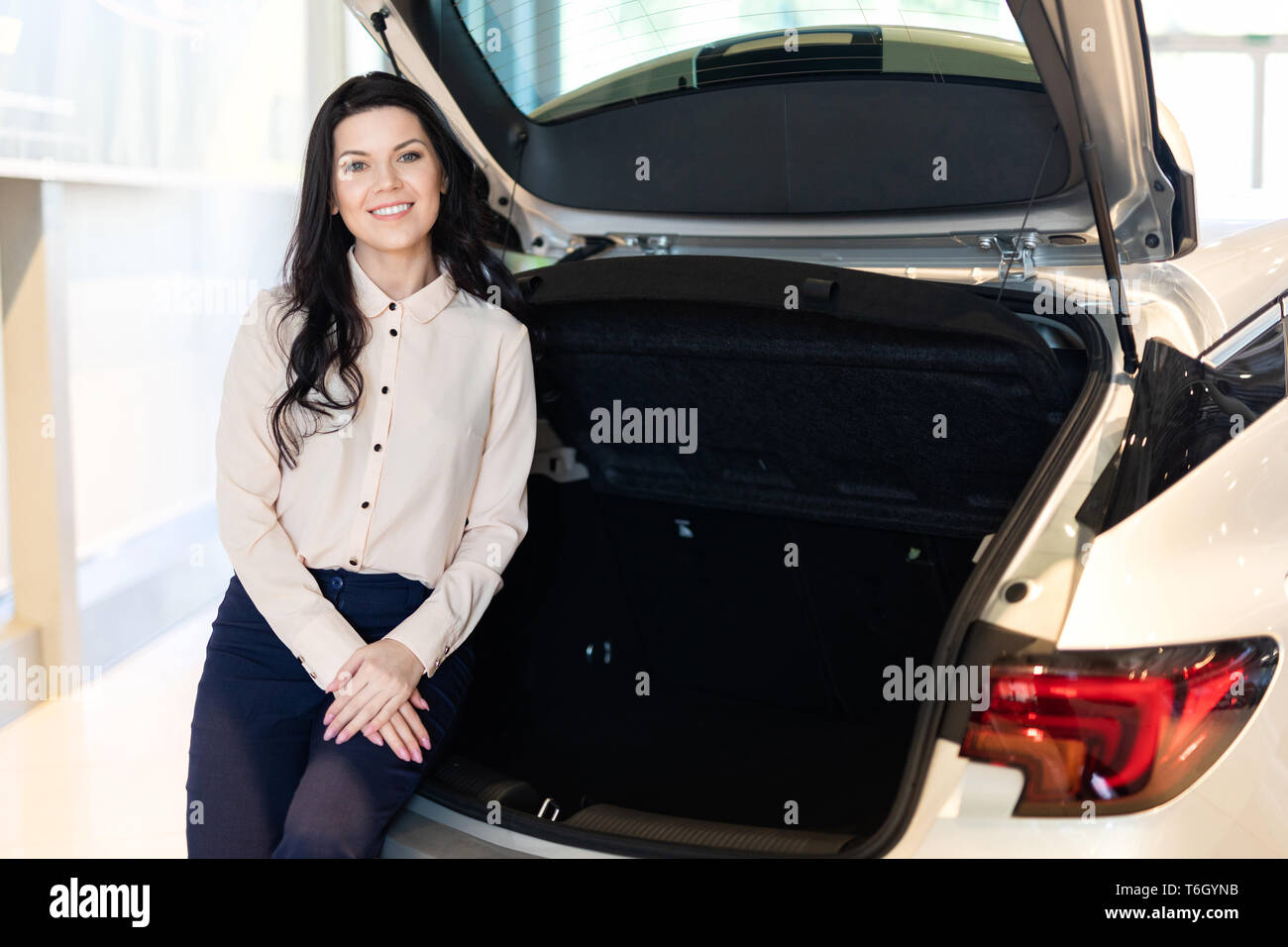 Beautiful saleswoman possing near new car in dealership center Stock ...