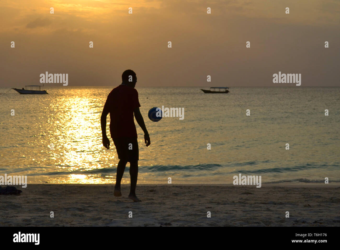 Man is playing beach football at the sunset Stock Photo - Alamy