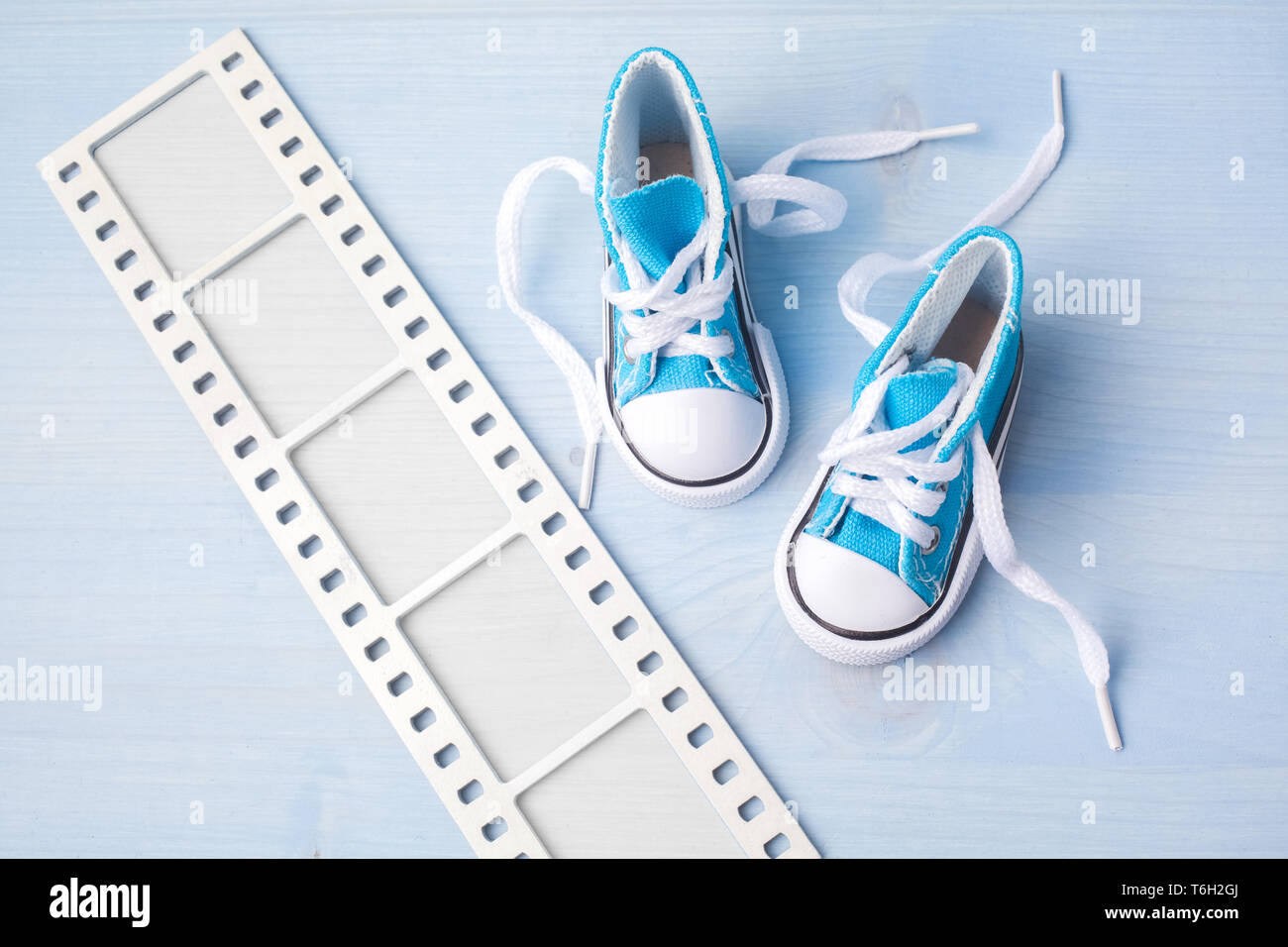 Cute tiny baby shoes on a wooden background with photo frame. Top view ...
