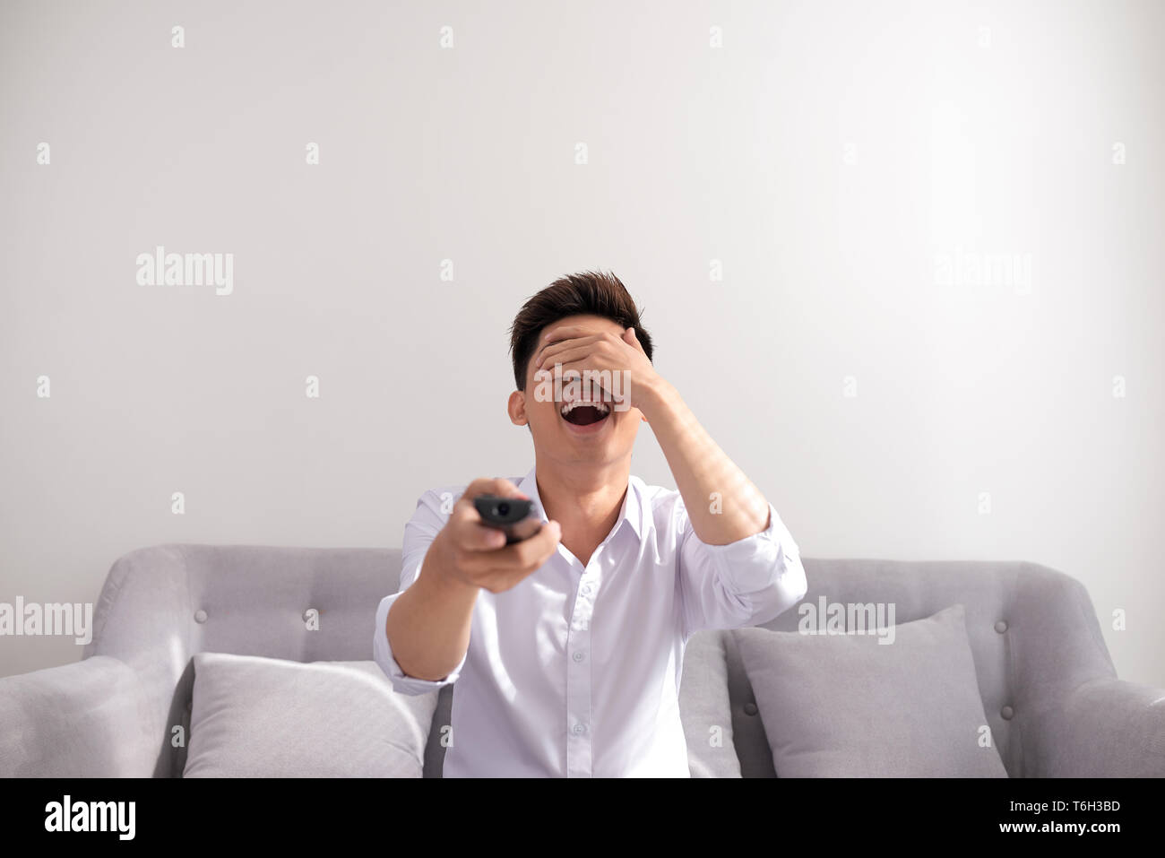 Great TV show.Handsome cheerful young man holding remote control and ...