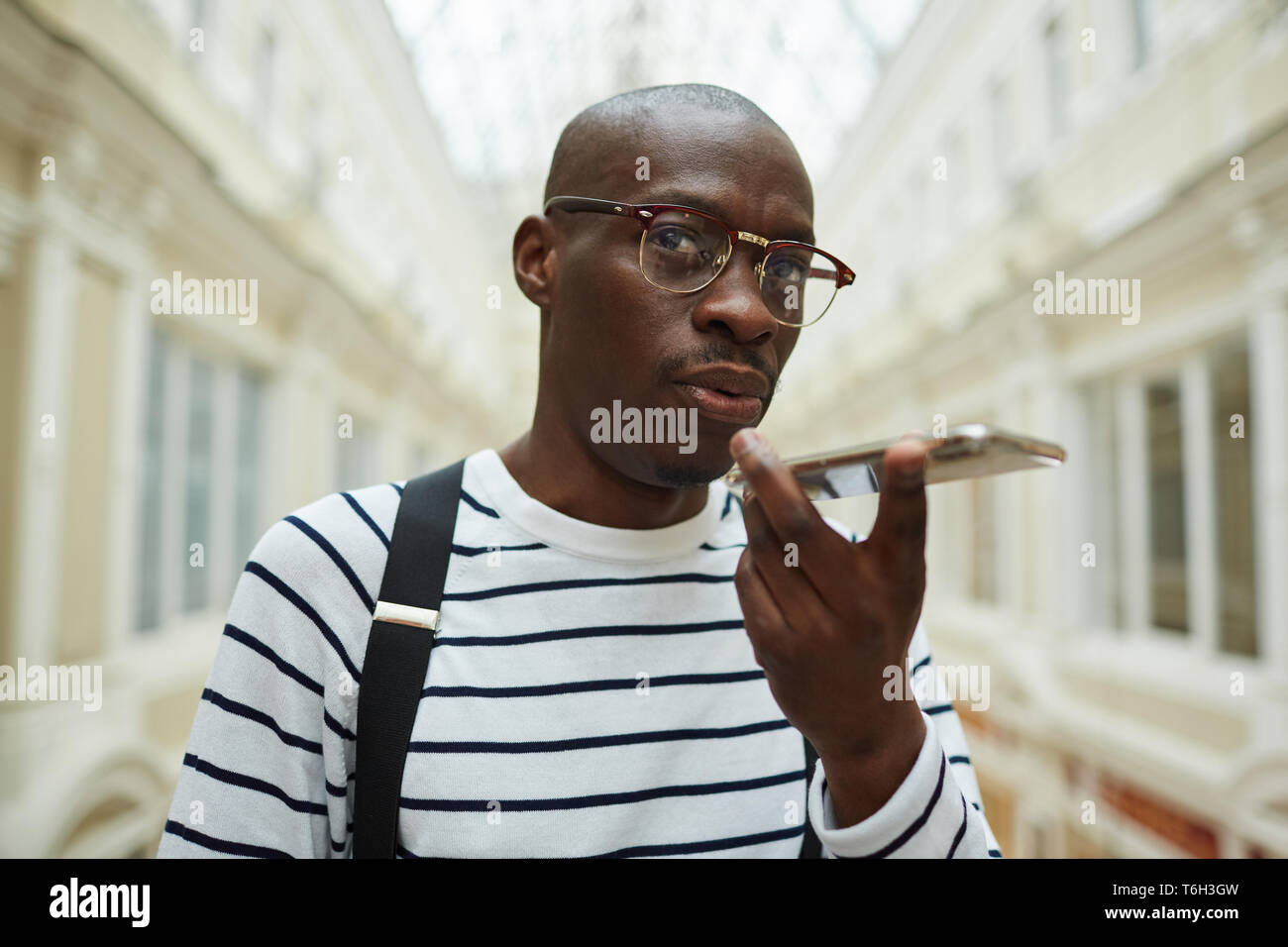 Portrait of contemporary African man speaking by phone on speaker ...