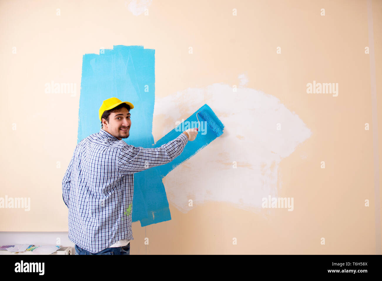 Painter man painting the wall at home Stock Photo - Alamy