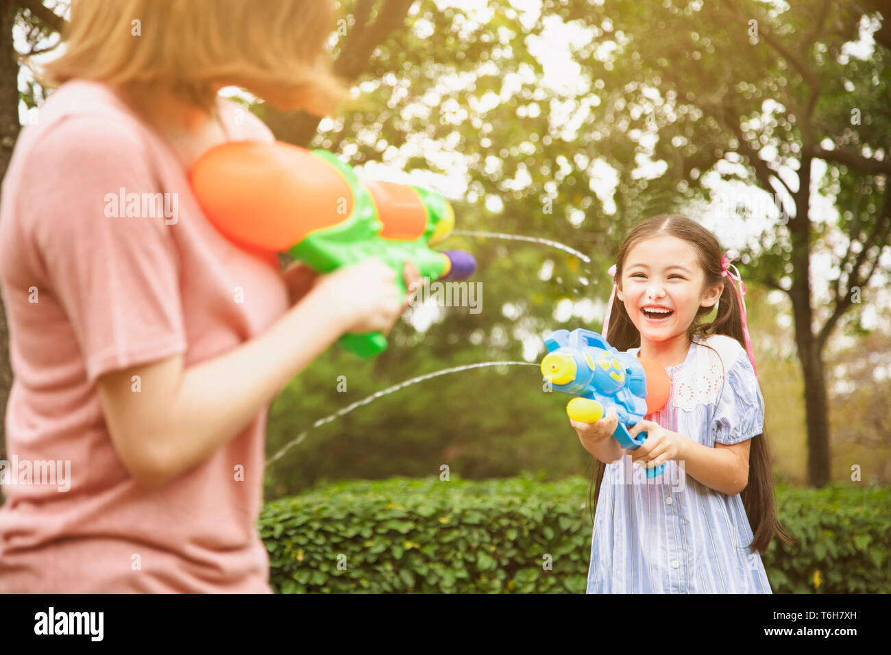 mother and little girls playing water guns in the park Stock Photo - Alamy