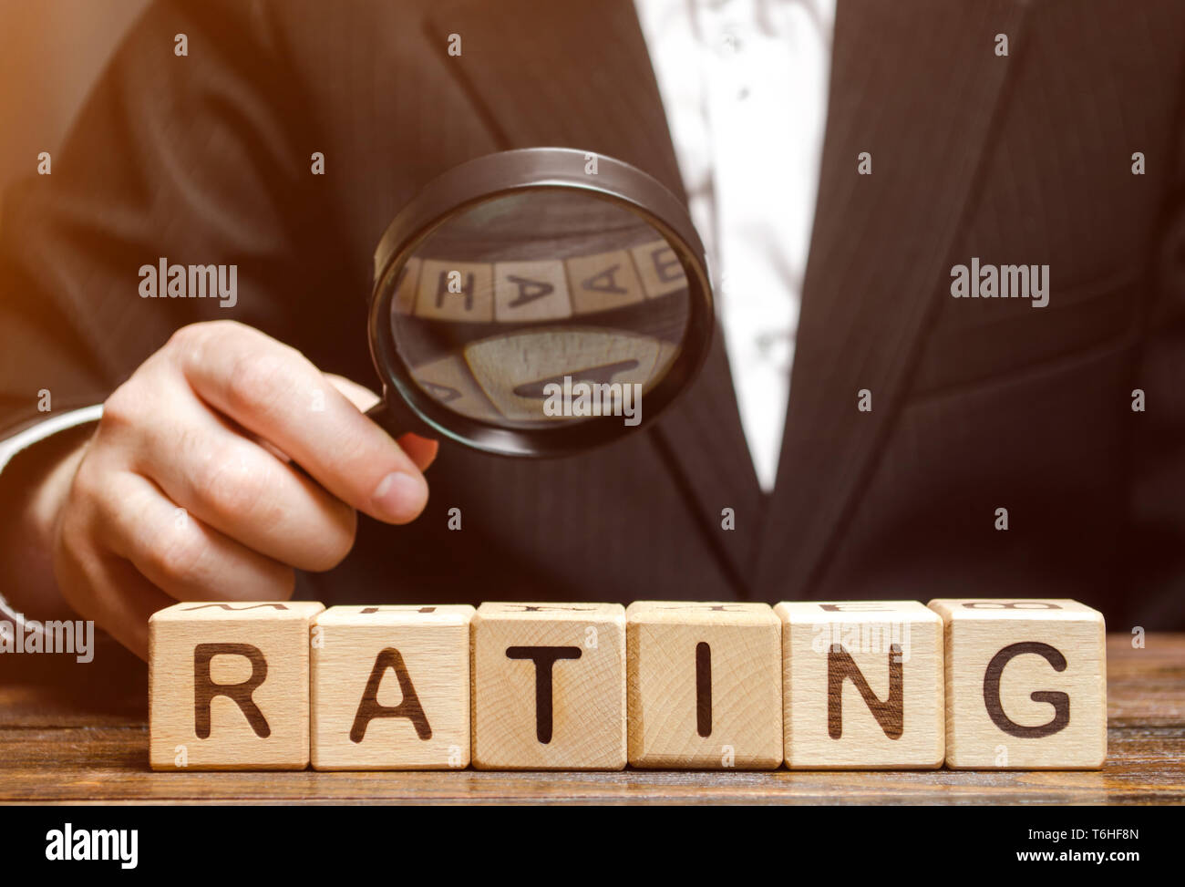 Wooden blocks with the word Rating and a magnifying glass in the hands ...
