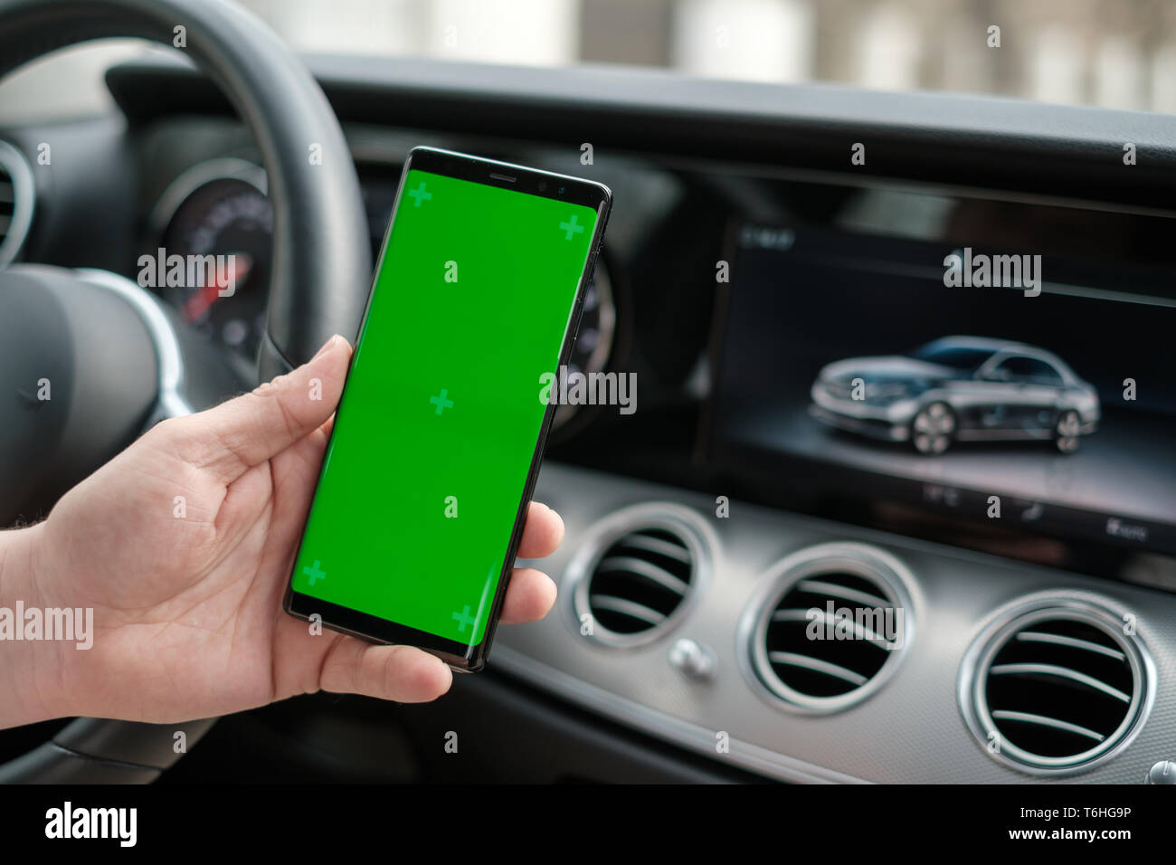 Man using smartphone on the background of a luxury class car dashboard ...