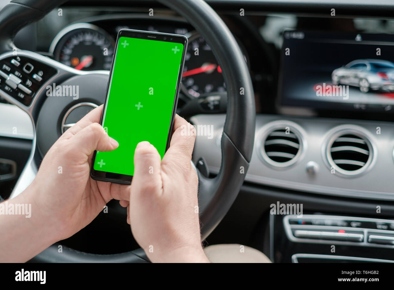 Man using smartphone on the background of a luxury class car dashboard ...
