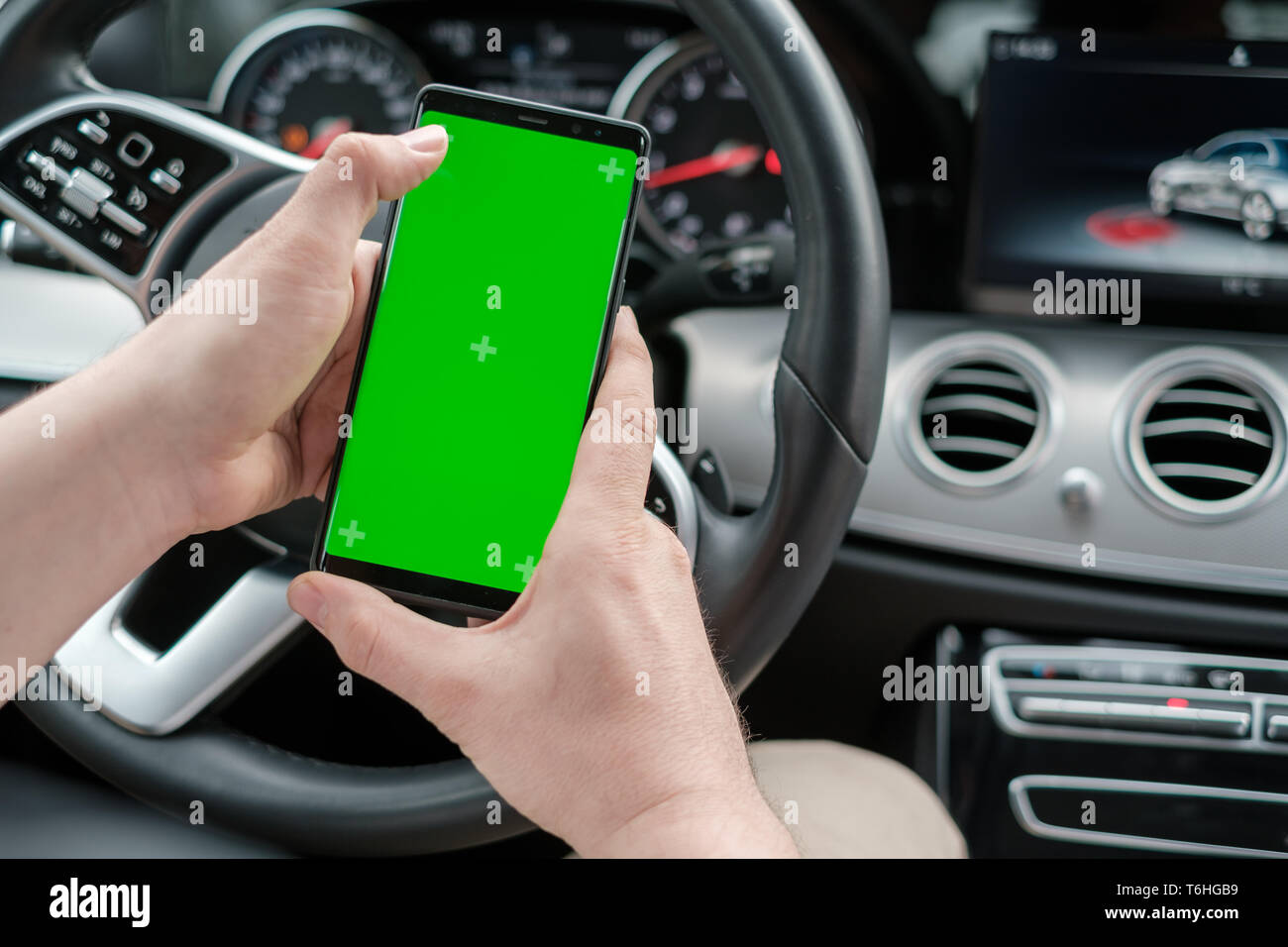 Man using smartphone on the background of a luxury class car dashboard ...