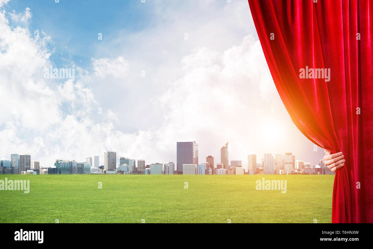 Green meadow behind red curtain and hand holding it Stock Photo - Alamy