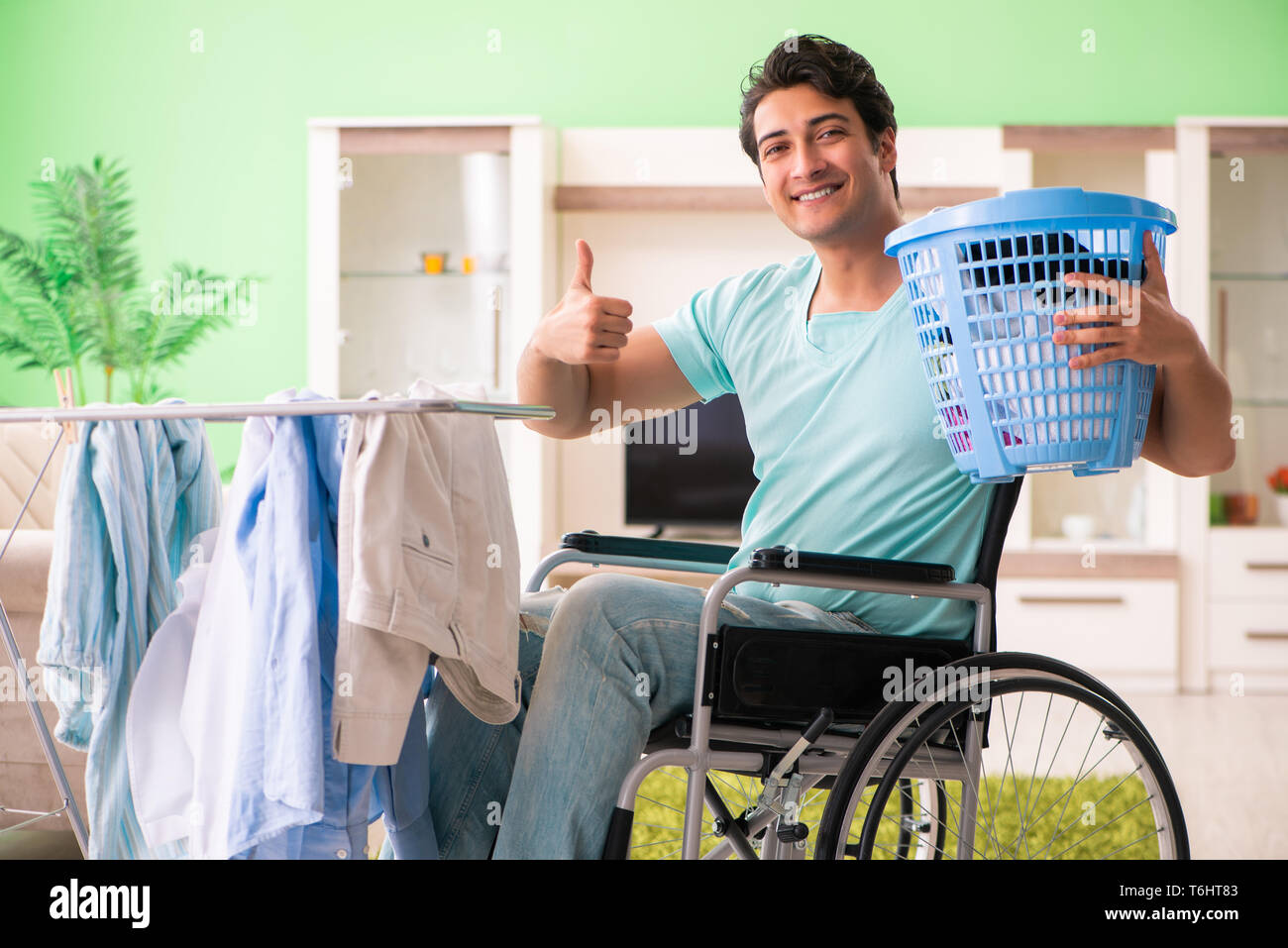 Disabled man on wheelchair doing laundry Stock Photo - Alamy