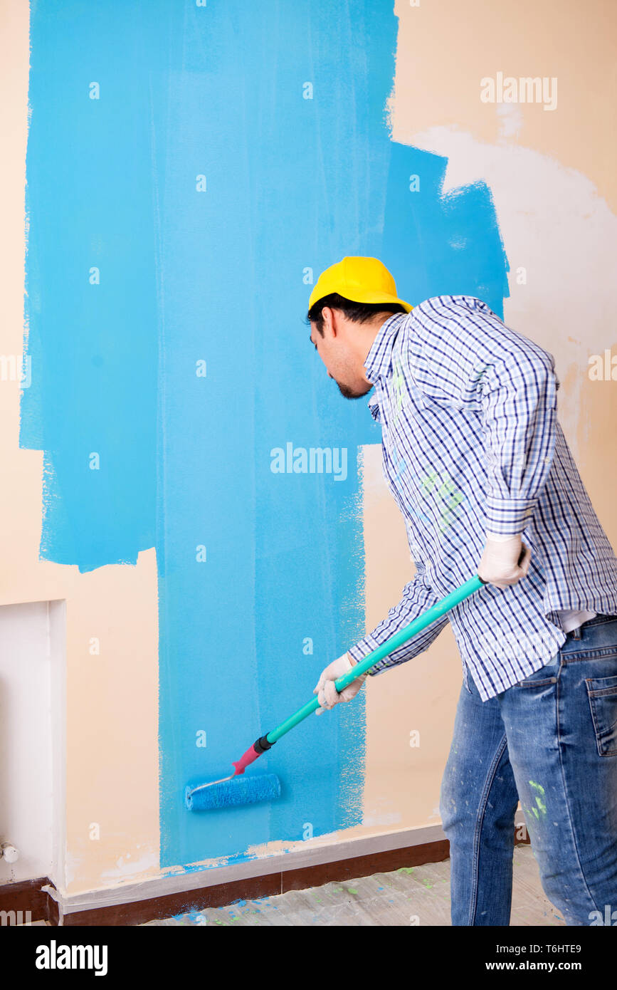Painter man painting the wall at home Stock Photo - Alamy