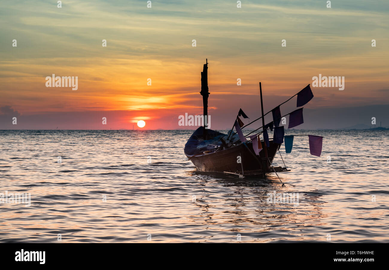 Wooden fishery boat floting on the sea with sunset time low lighting ...