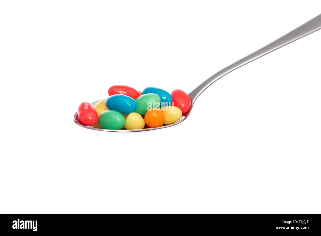 Multi-colored candies in a spoon on white background Stock Photo - Alamy