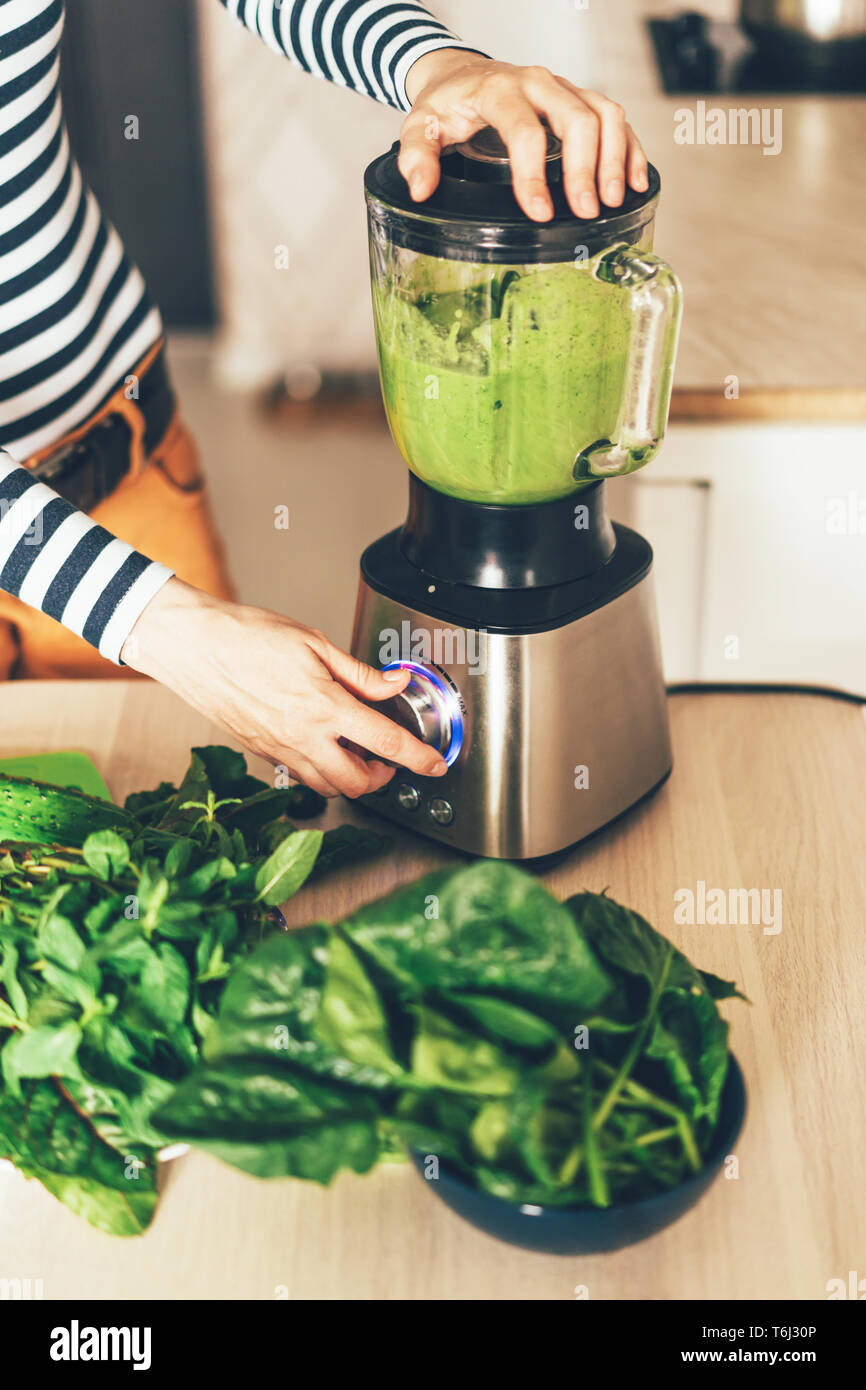 Cooking smoothies, a woman in the interior of her kitchen preparing a ...