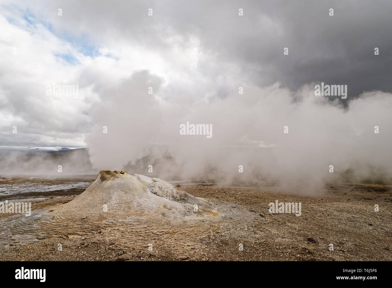 Volcanic landscape with a large fumarole, which releases a lot of steam ...