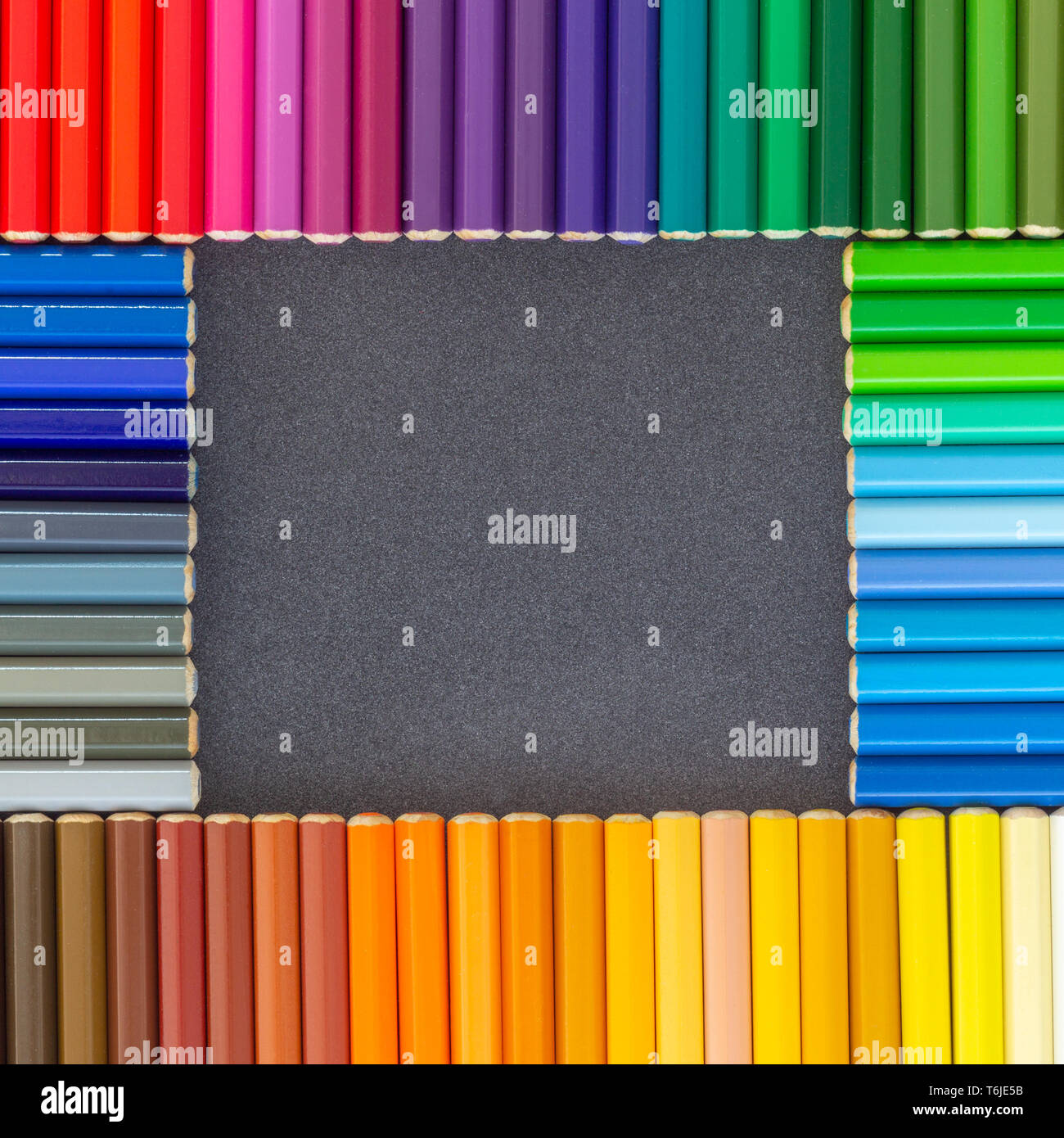 Сolored pencils laid out in the form of a square with dark background ...