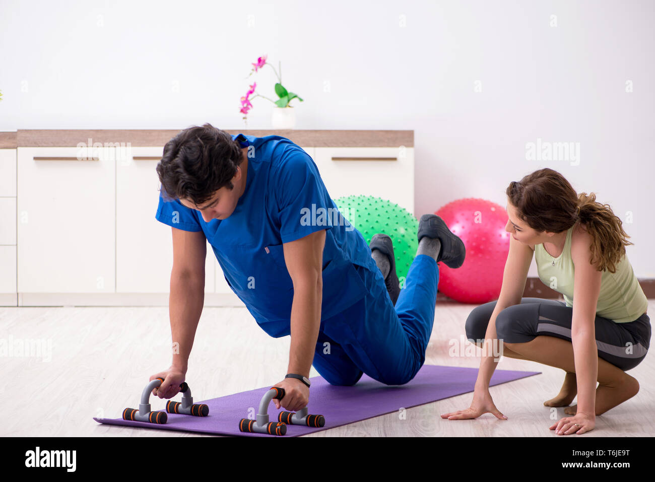 Fitness instructor helping sportsman during exercise Stock Photo - Alamy