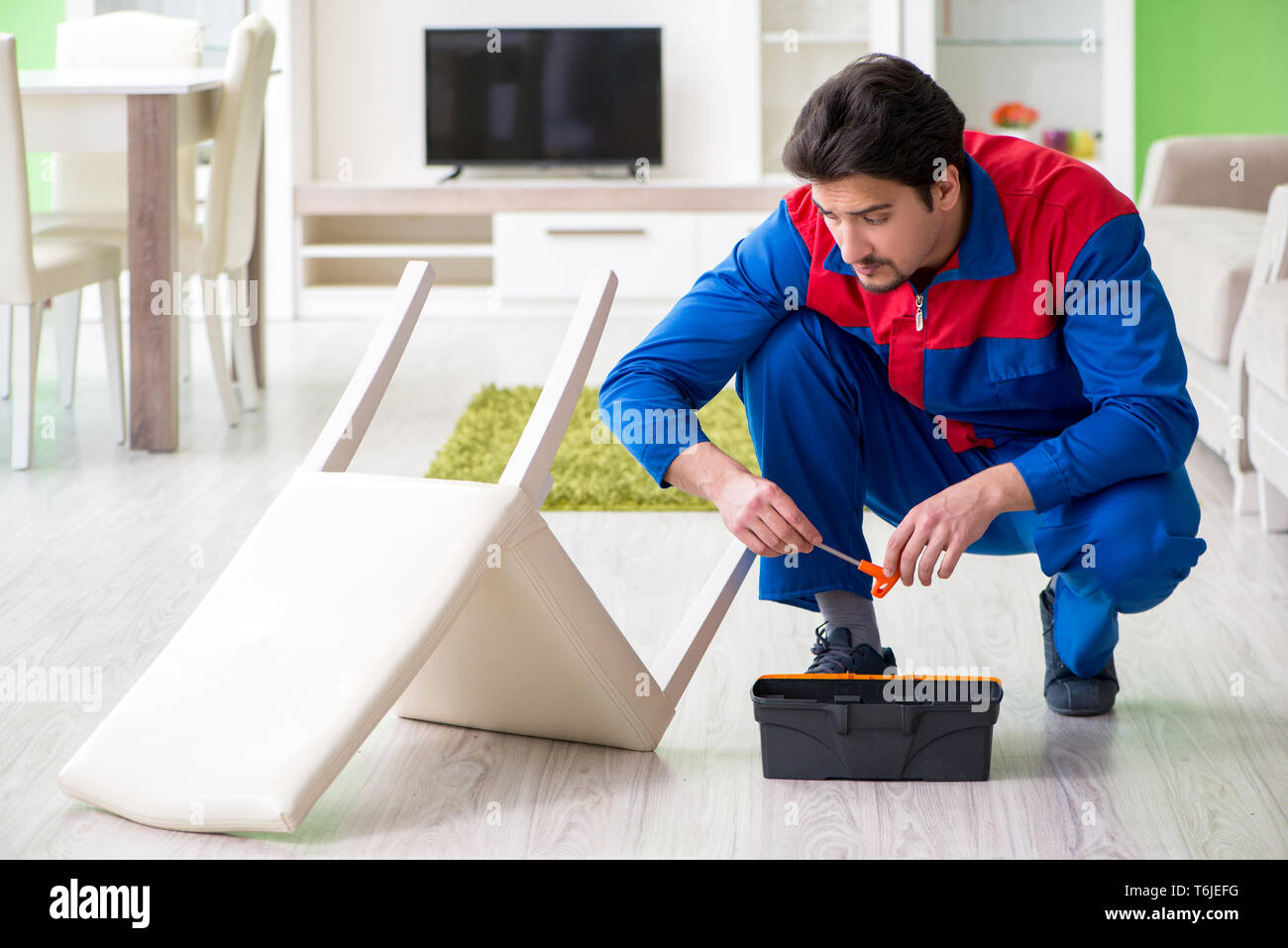 Repair contractor repairing broken chair at home Stock Photo - Alamy