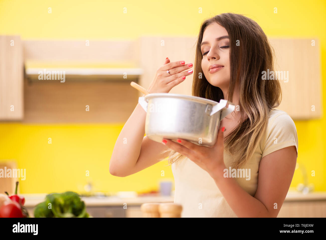 Young woman cooking soup in kitchen at home Stock Photo - Alamy
