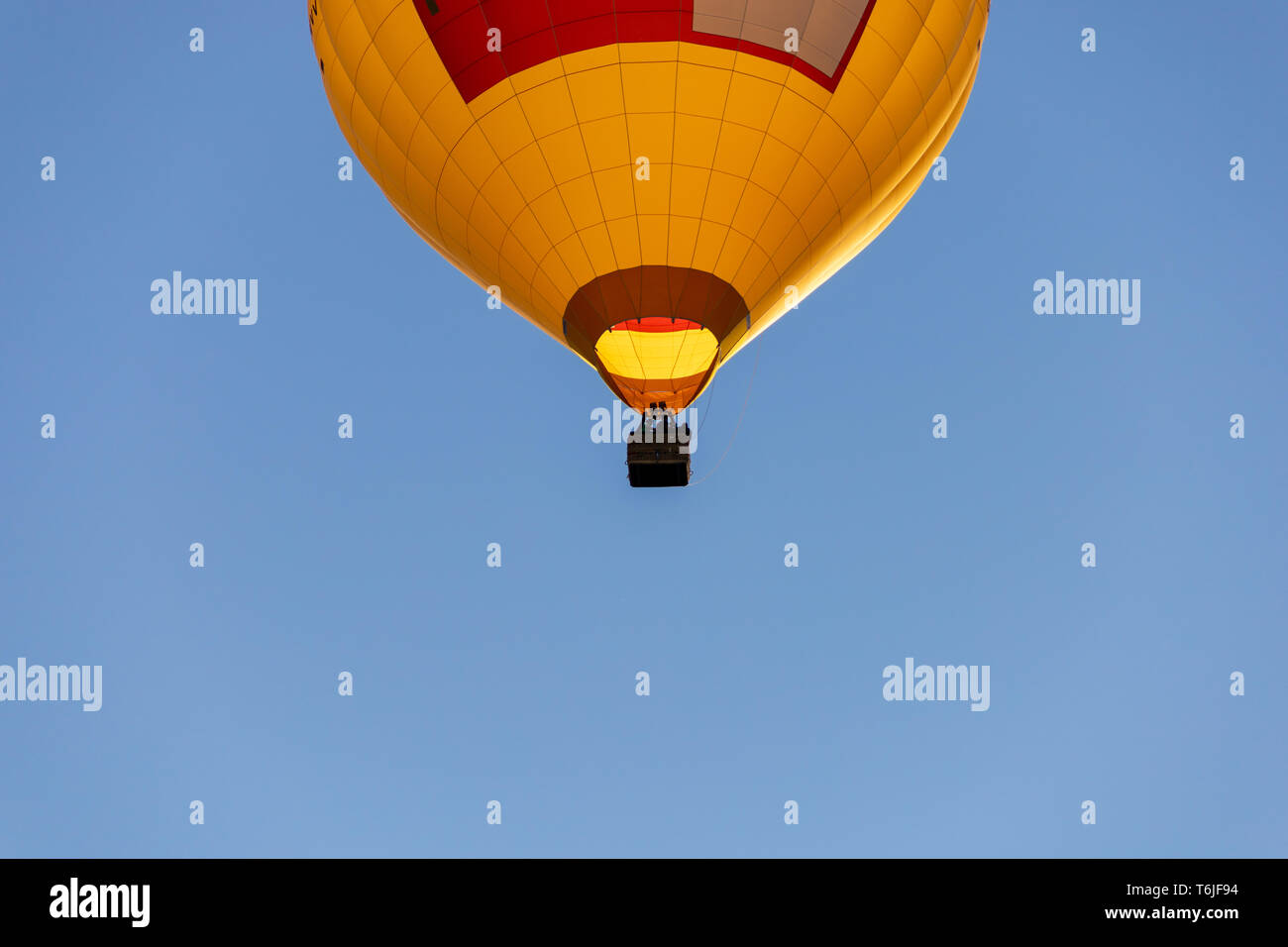 yellow hot air balloon with a group of people against clear sky Stock ...