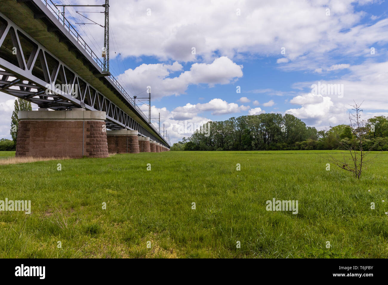 Meadow with a train bridge leading into far view. Clouds over the ...