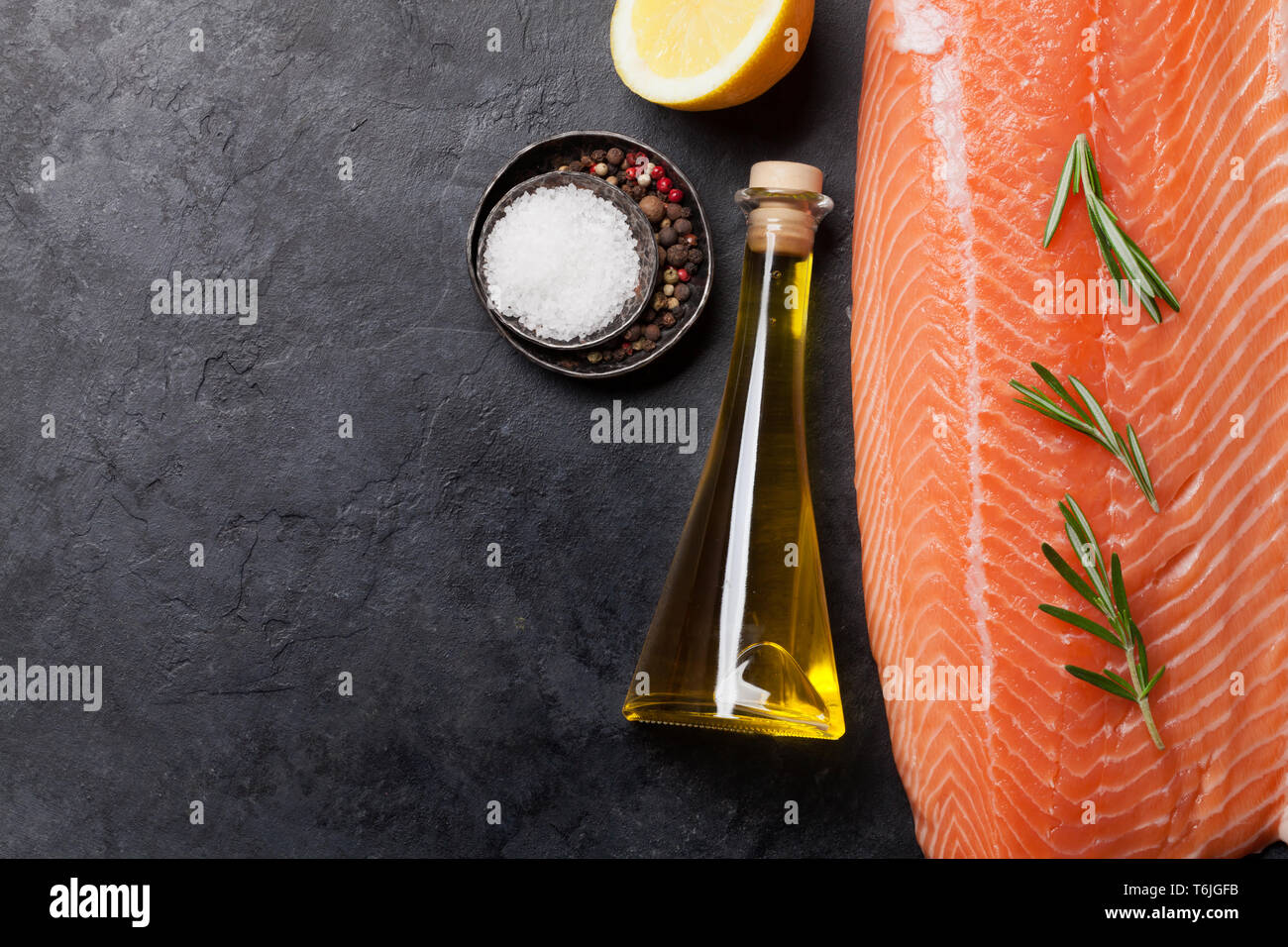 Raw salmon fish fillet and ingredients for cooking on stone table. Top ...