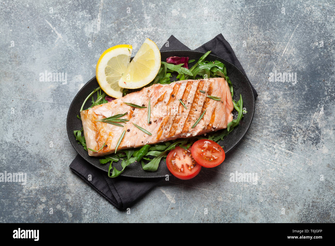 Grilled salmon fish fillet with salt, pepper and rosemary over salad ...