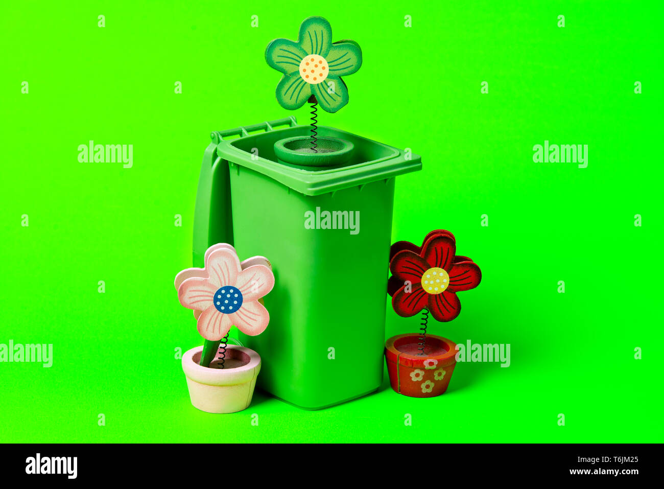 Green trash can with flowers on a green background Stock Photo - Alamy