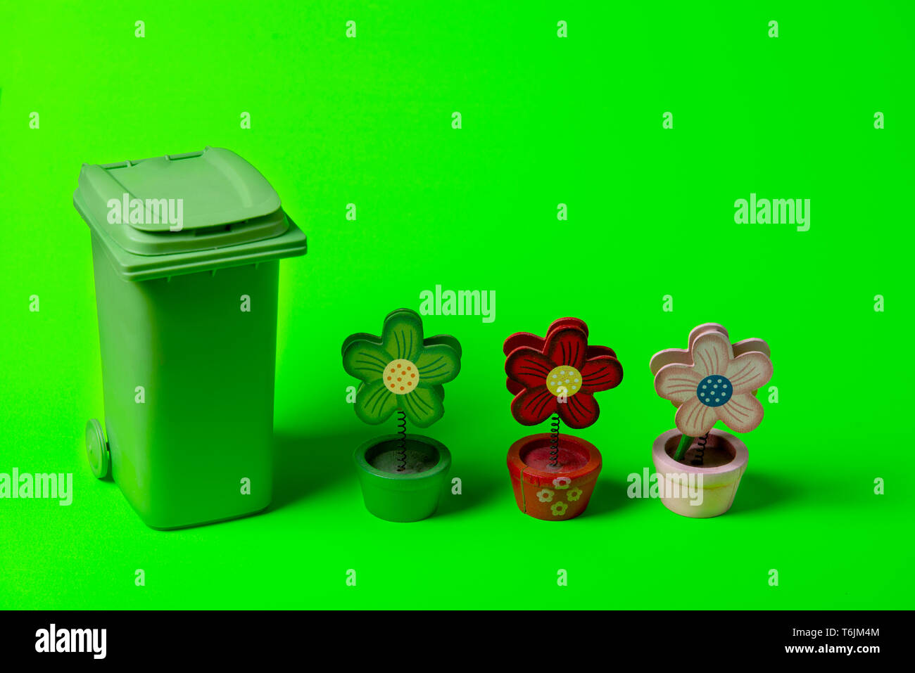 Green trash can with flowers on a green background Stock Photo - Alamy