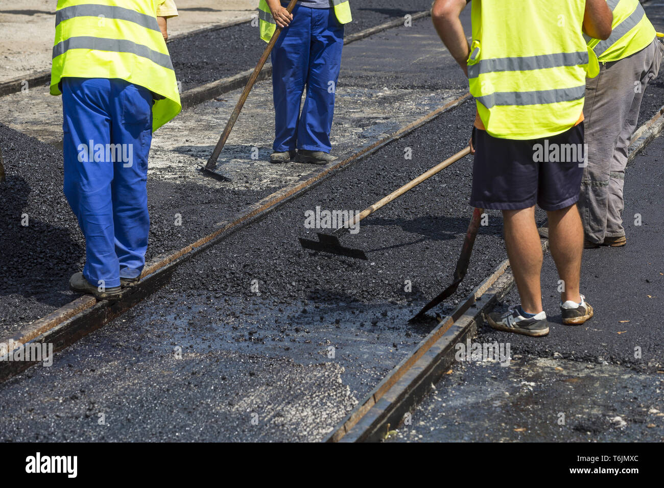 Workers construct asphalt road and railroad lines Stock Photo - Alamy