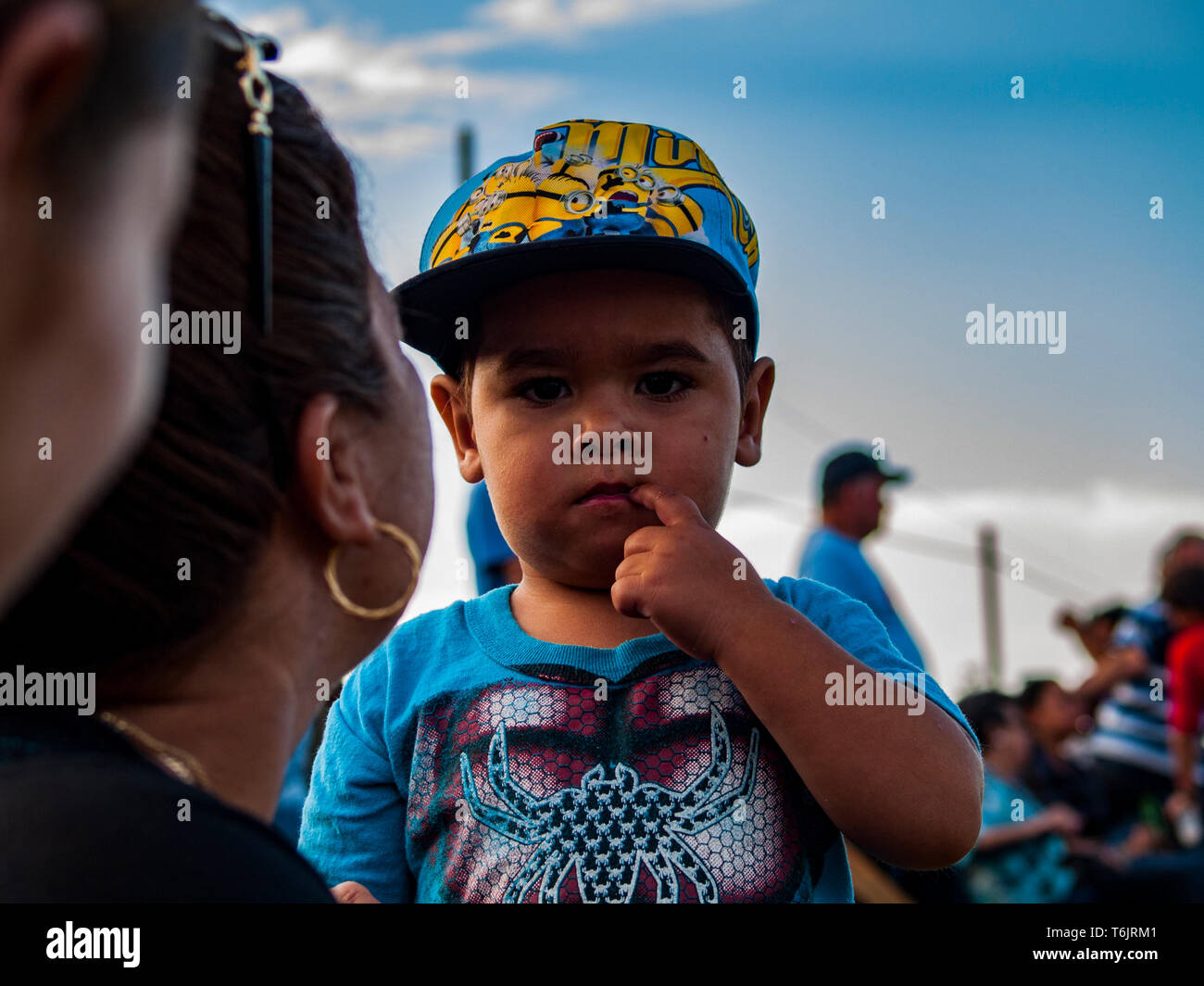 child with cap and blue pullover with drawings and fingers in the mouth ...