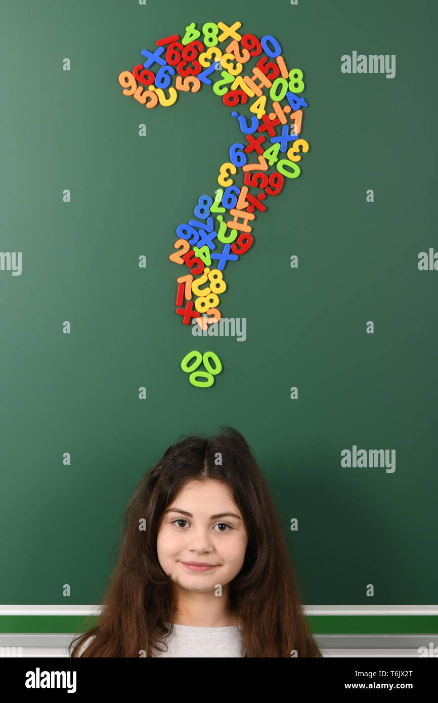 Smiling little schoolgirl on green school board. A magnetic question ...
